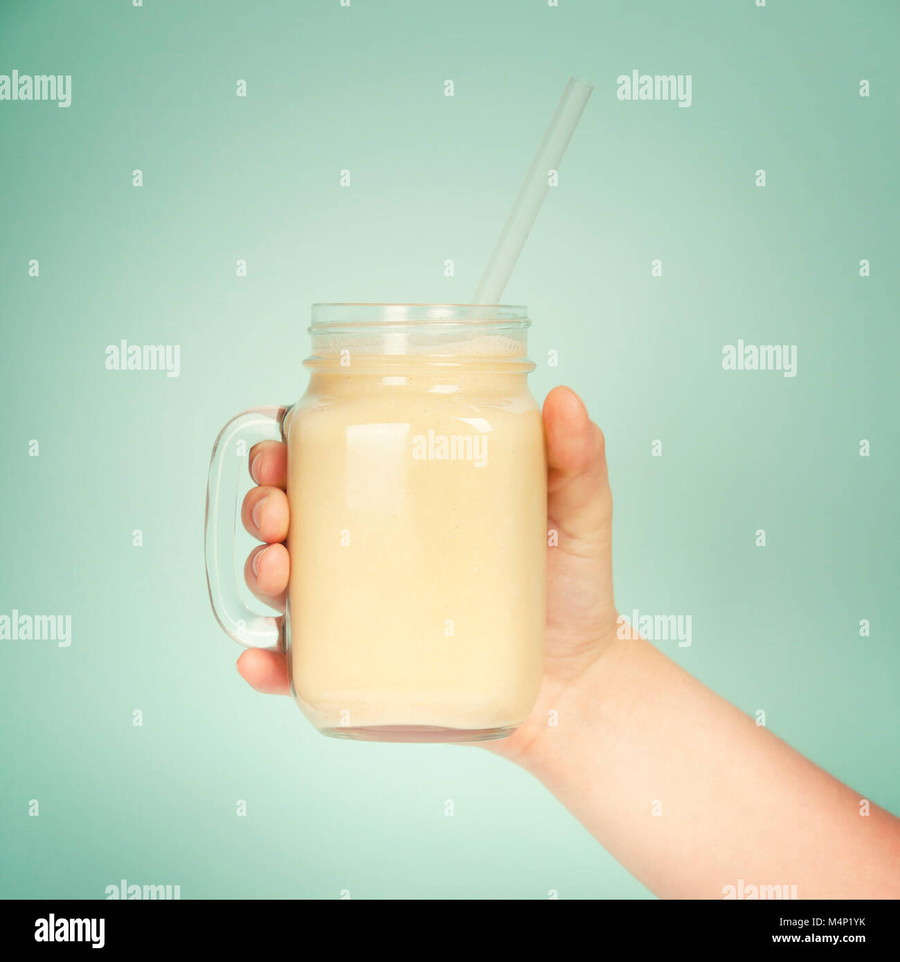 Womans hand holding smoothie shake against bright wall. Drinking ...