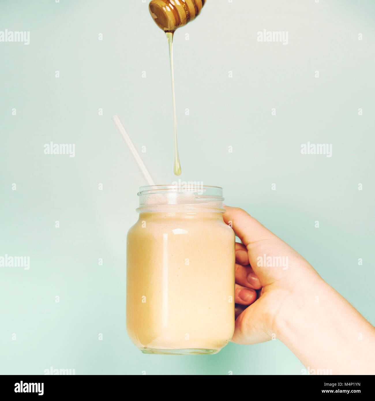 Womans hand holding smoothie shake against bright wall. Drinking ...