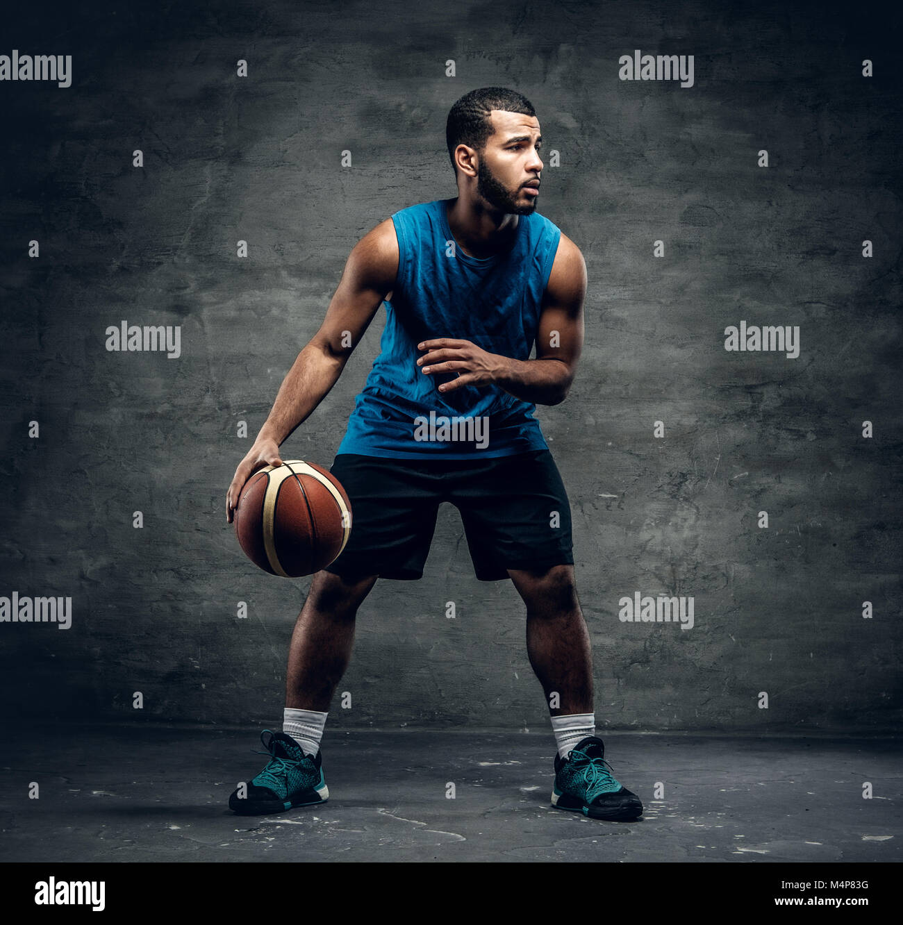 Full body studio portrait of a black basketball player playing with a ...