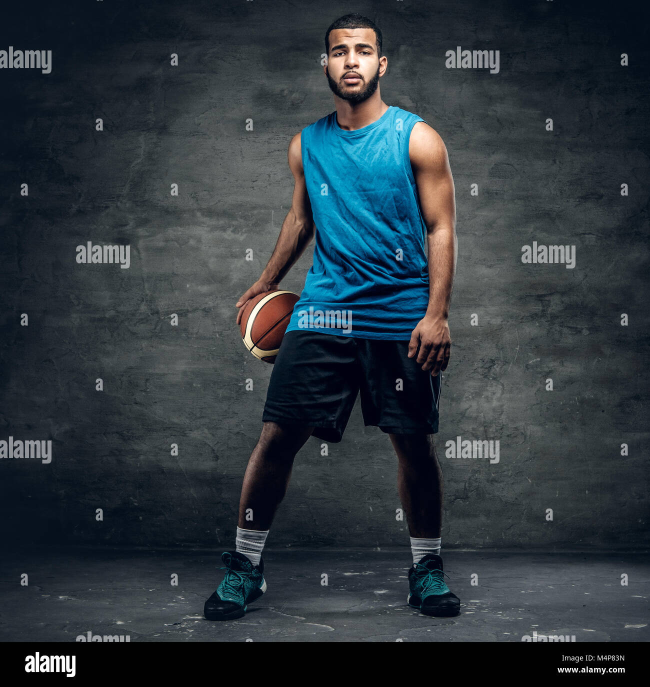Full body studio portrait of a black basketball player playing with a ...