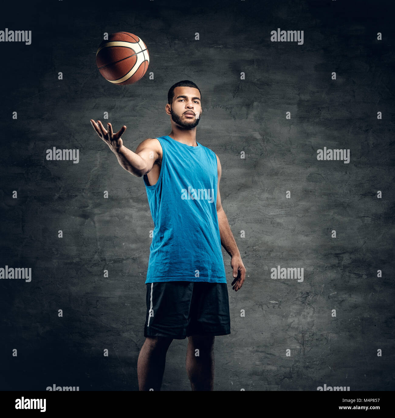 Full body studio portrait of a black basketball player playing with a ...