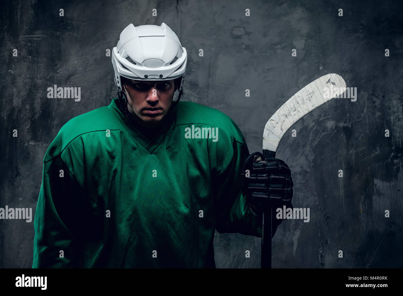 Portrait of tired hockey player in protective uniform in a shadow on ...