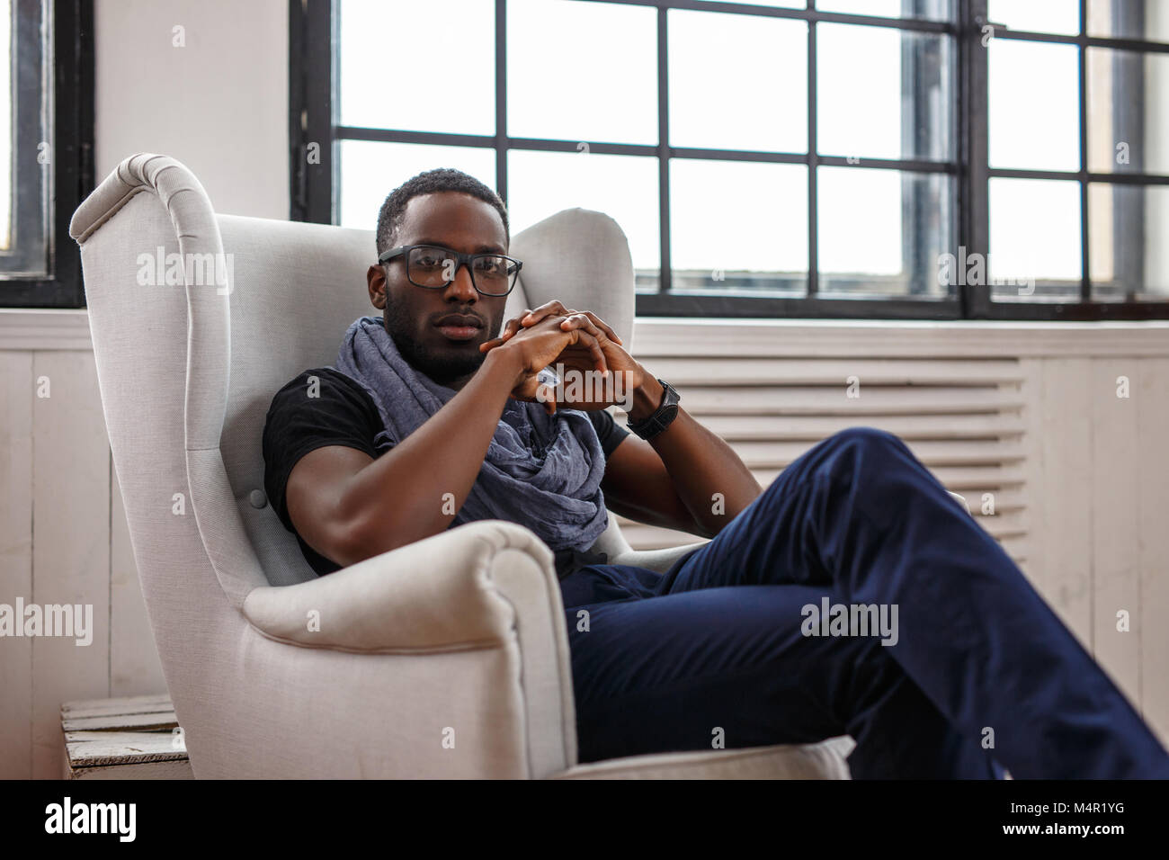 A black man relaxing in a white chair.Studio shot Stock Photo - Alamy