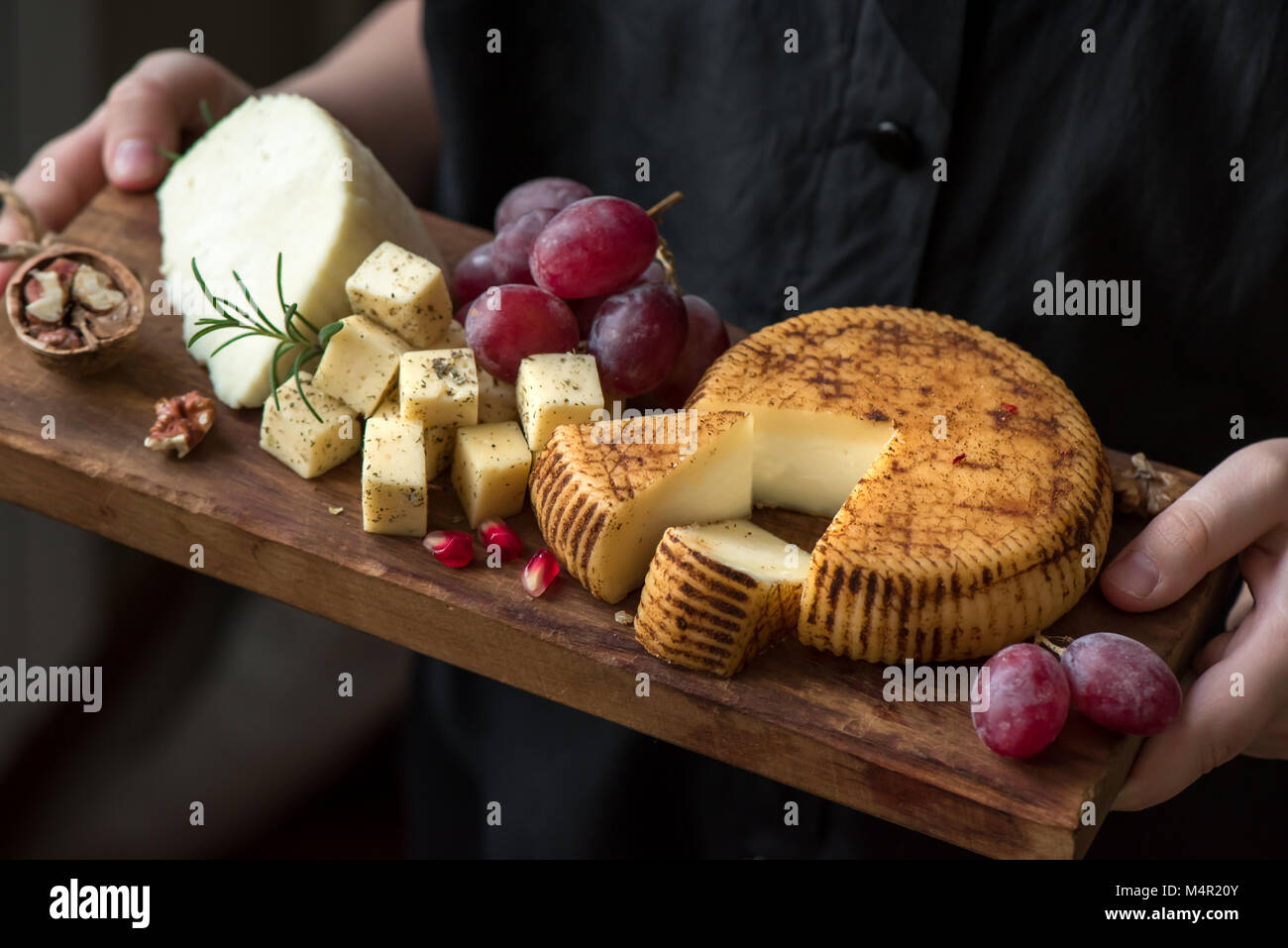 Rustic gourmet cheese platter in hands of cheese maker, close up ...