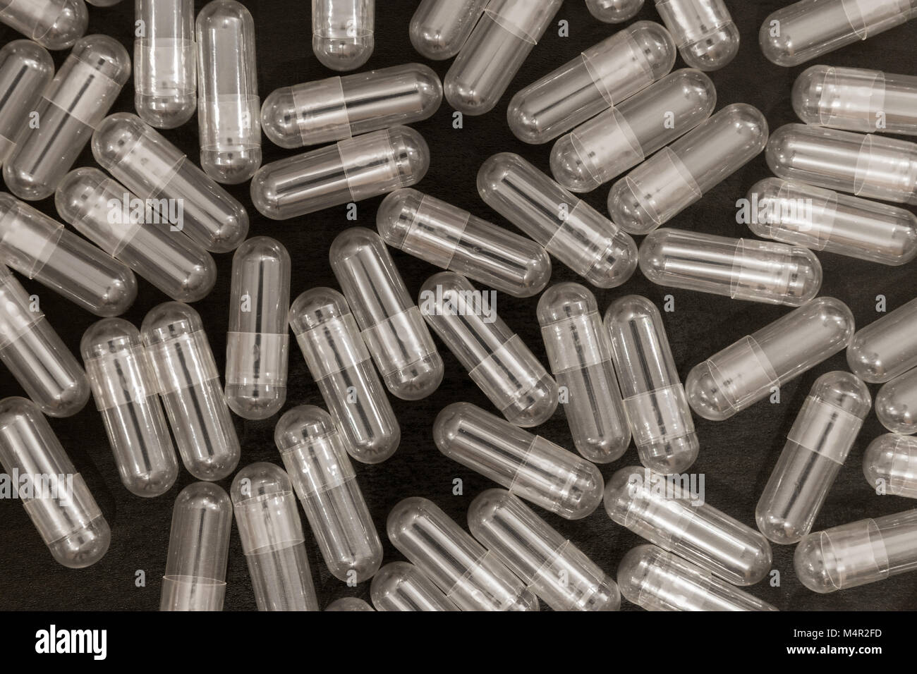 Clear vegetable capsules on dark background. Capsules used to fill with ...