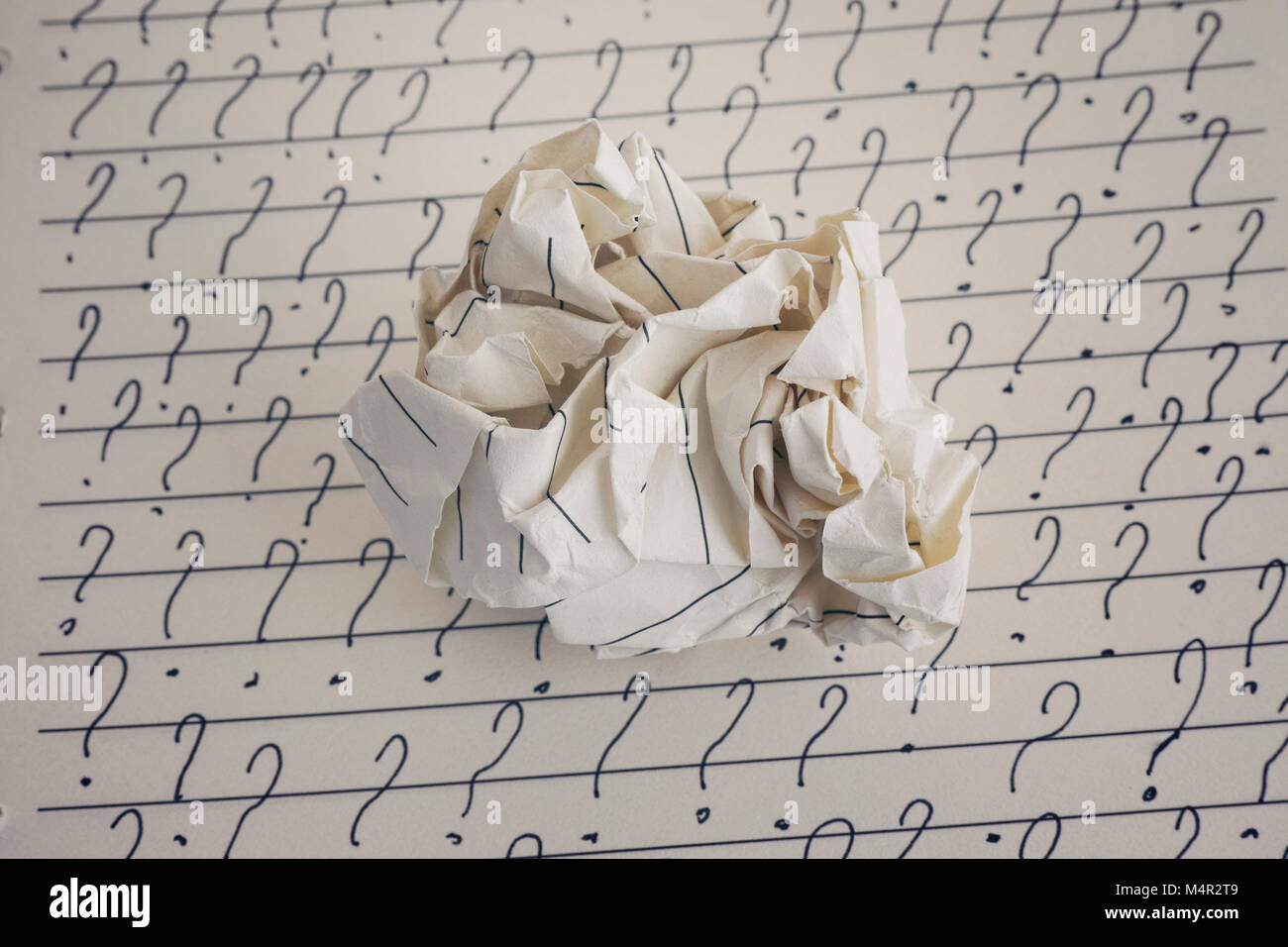 Crumpled paper ball and question marks on sheet of lined paper. Close ...