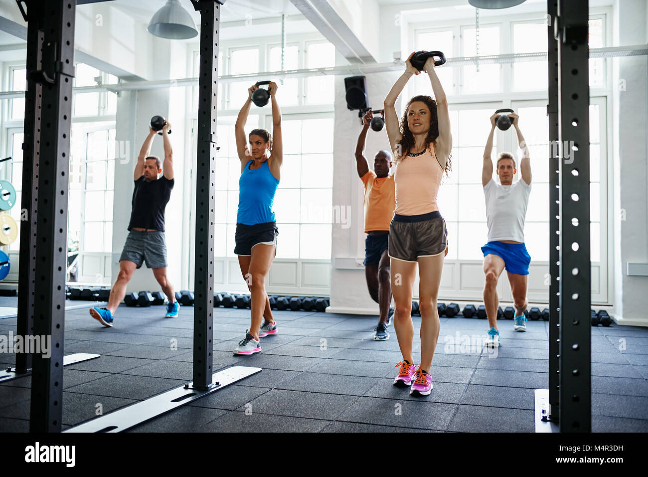 Diverse group of young people working out together with weights in a ...