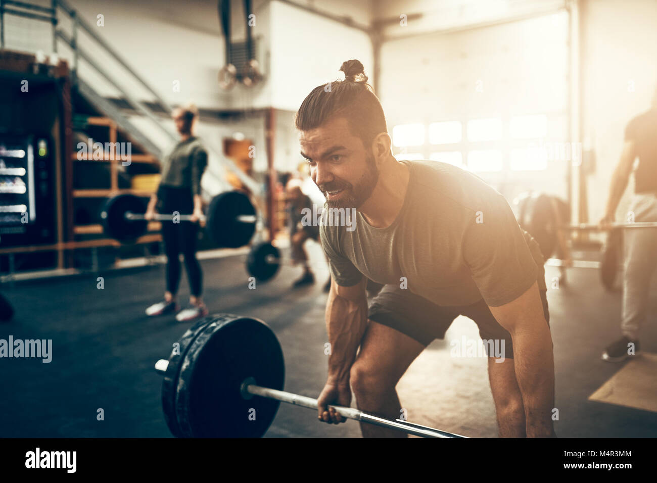 Fit young man in sportswear straining to lift heavy weights while ...