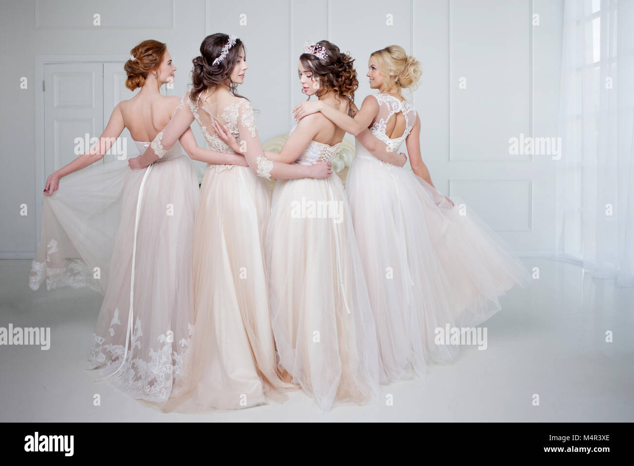 Bride in wedding salon. Four beautiful girl are in each other's arms ...