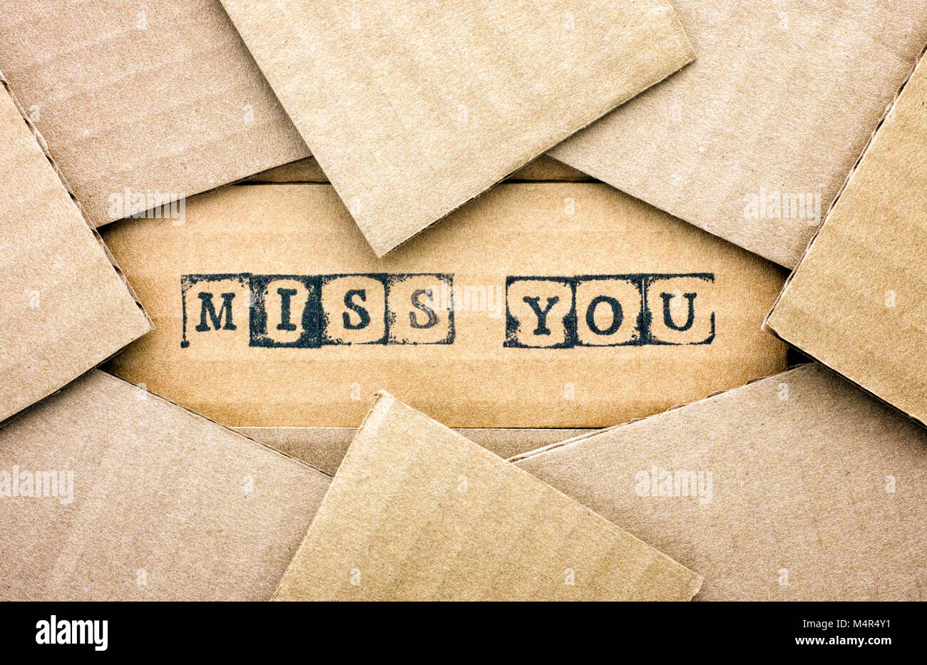 Words Miss You make by black alphabet stamps on cardboard with some ...
