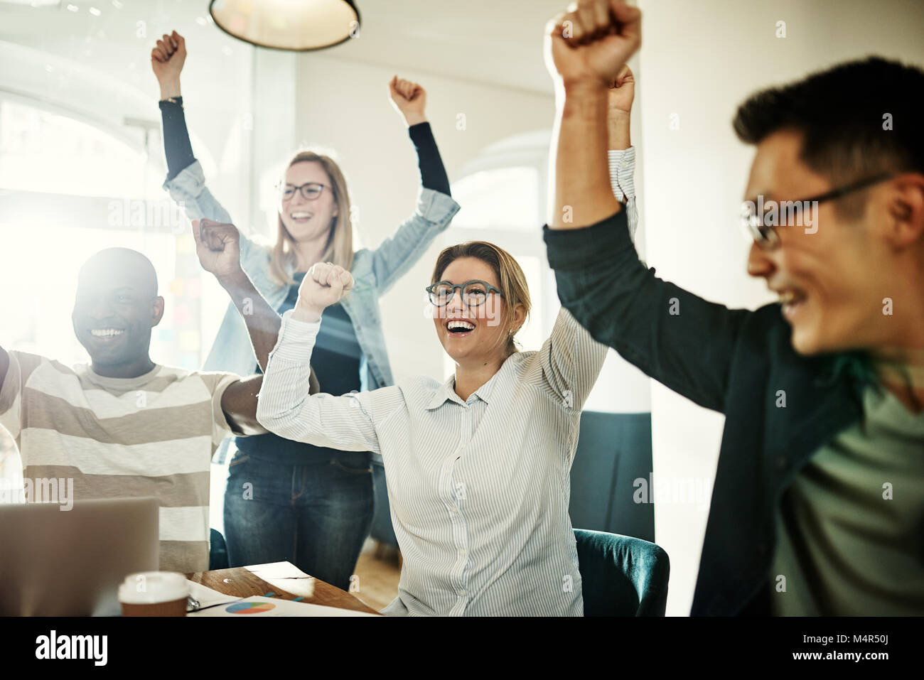 Diverse group of ecstatic businesspeople cheering during a presentation ...