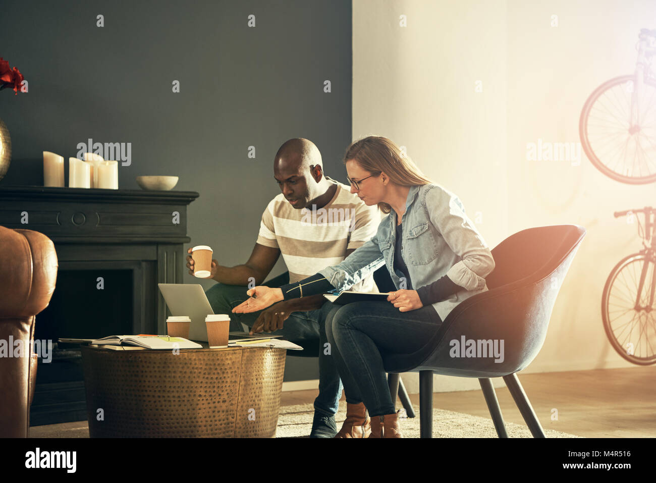 Two diverse colleagues sitting together in a stylish modern office ...