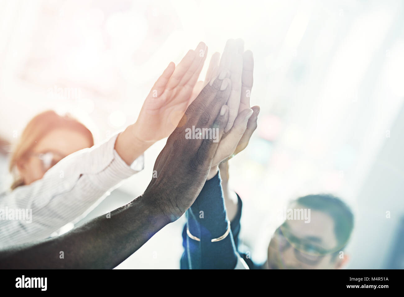 Diverse group of smiling business colleagues high fiving each other ...