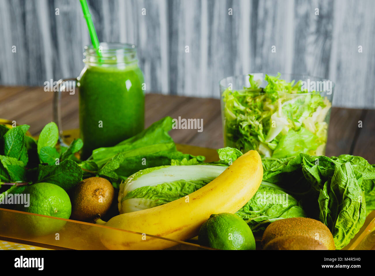 Blended green smoothie with ingredients on wooden table selective focus ...