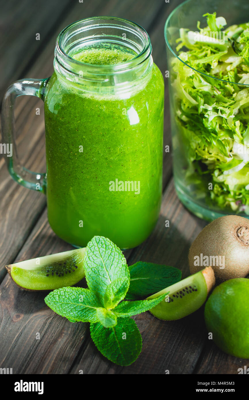 Blended green smoothie with ingredients on wooden table selective focus ...