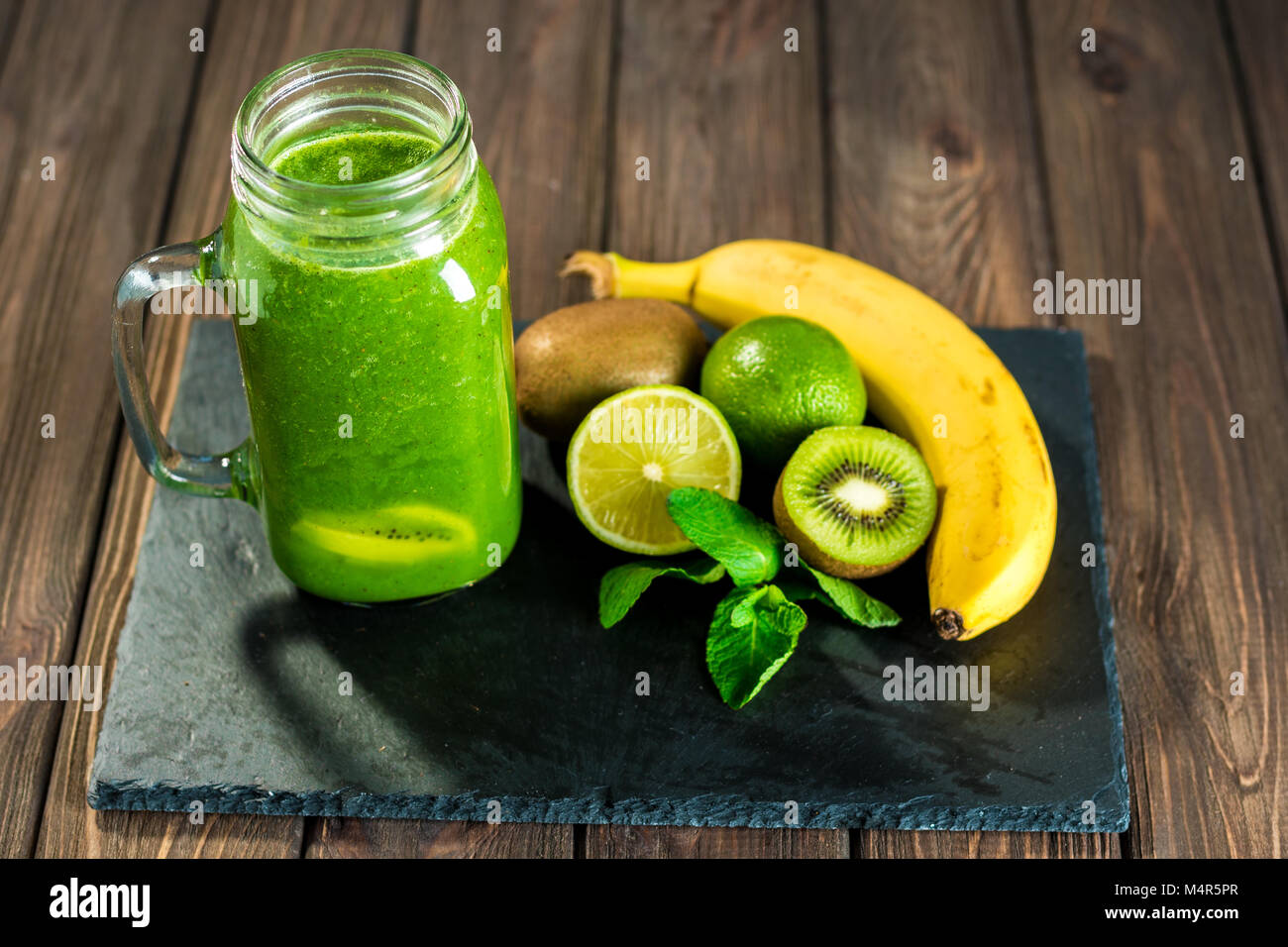 Blended green smoothie with ingredients on the stone wooden table ...