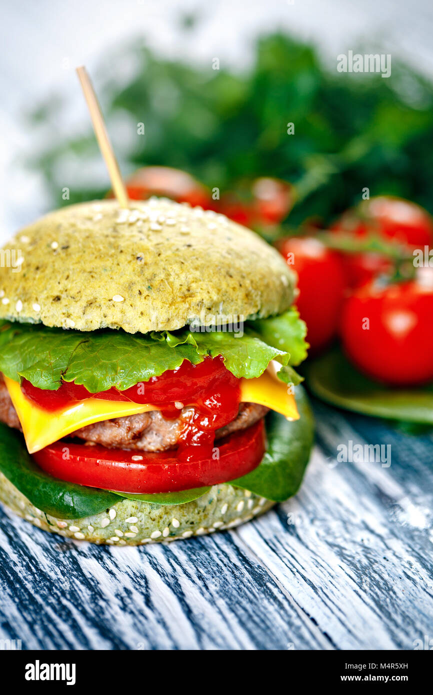 burger with green bun and fresh vegetables white on wooden background ...