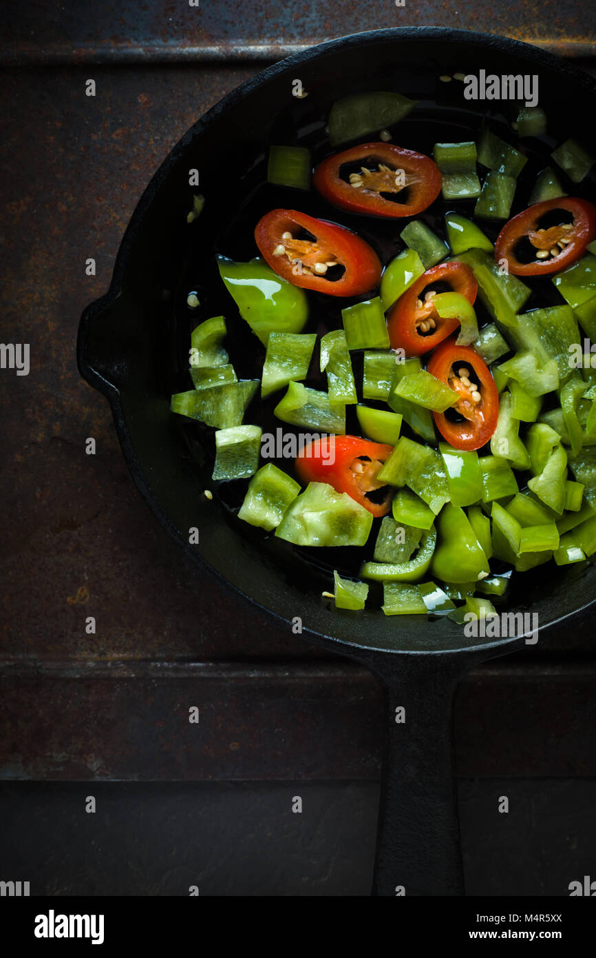Green pepper and chili on a cast-iron frying pan vertical Stock Photo ...
