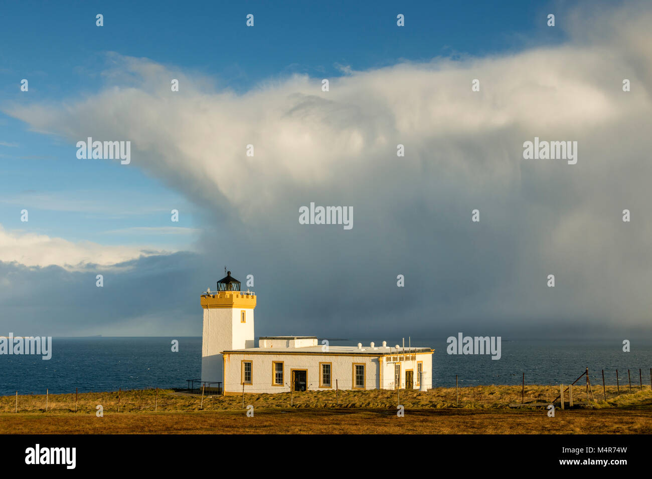 Duncansby Head lighthouse with a cumulonimbus shower cloud behind ...