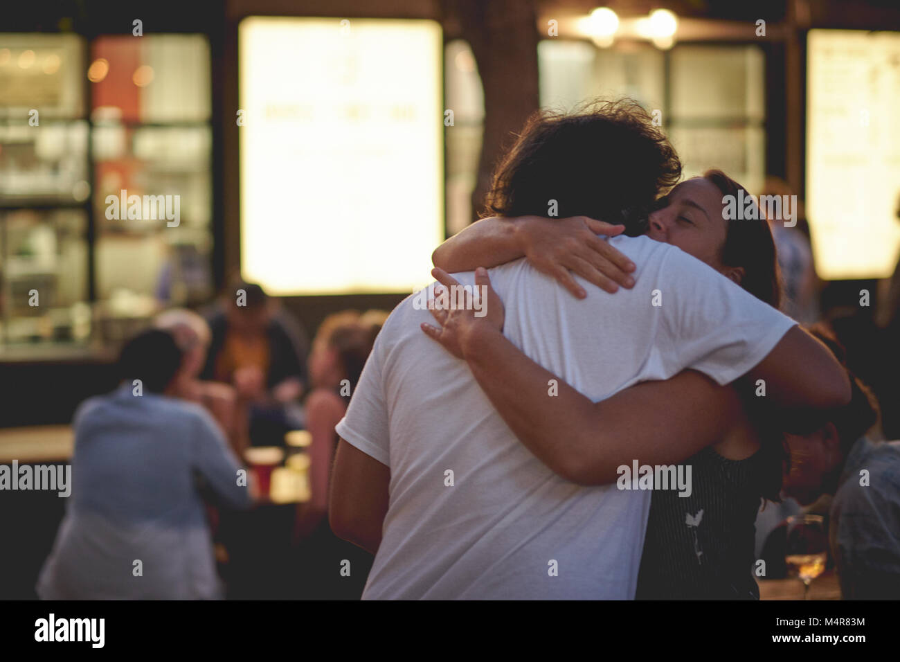 Friends embracing at a cafe Stock Photo - Alamy