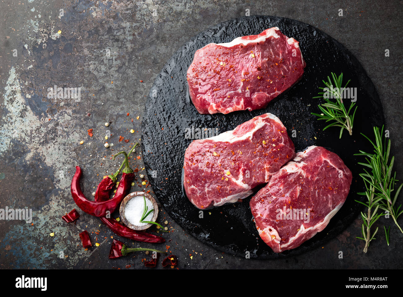 Raw beef meat. Fresh steaks on slate board on black background. Top ...