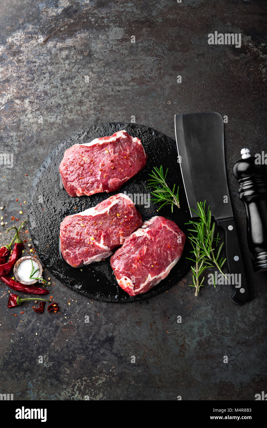 Raw beef meat. Fresh steaks on slate board on black background. Top ...