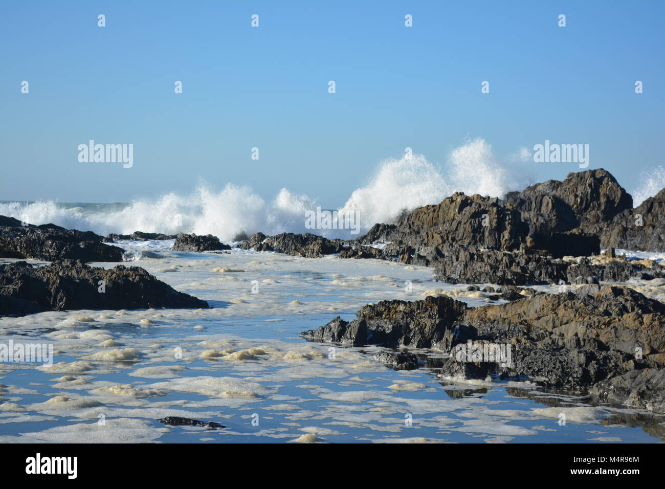 Foamy water in the rockpools after sea Waves in background crashing ...