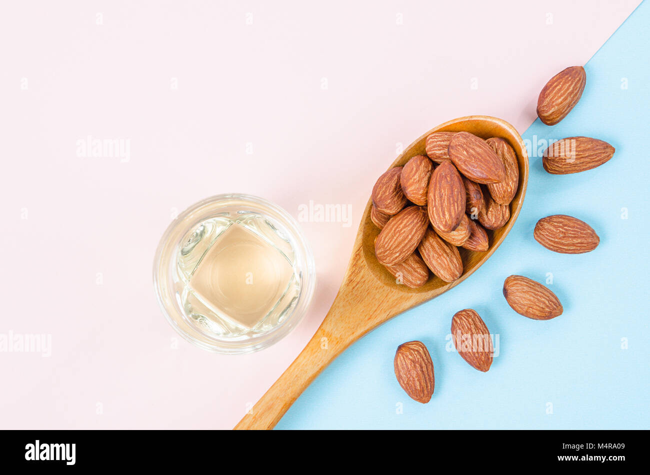 Peeled almonds seeds with almond oil on color paper background with ...