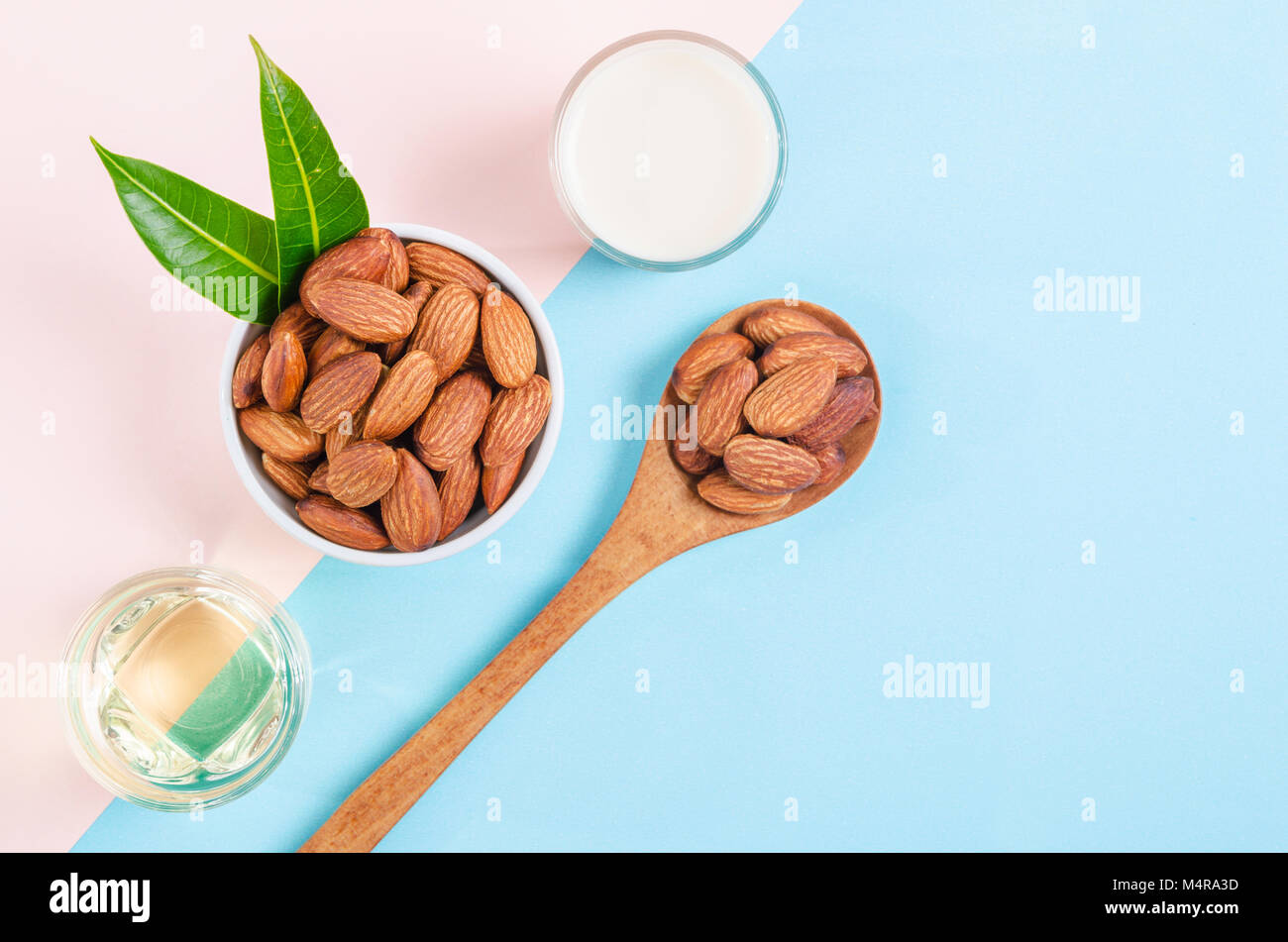Peeled almonds with white bowl and cup of almond milk and oil on color ...