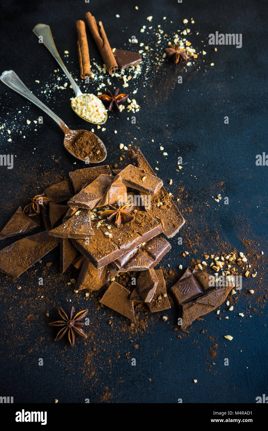 Dark chocolate pieces crushed on dark wooden table, spices like a ...