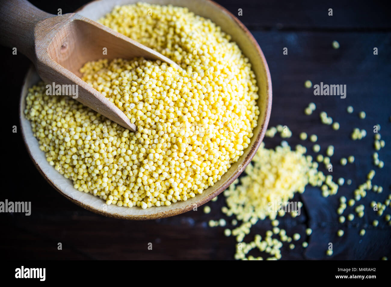 organic raw millet seeds in a rustic bowl on wooden table with ...