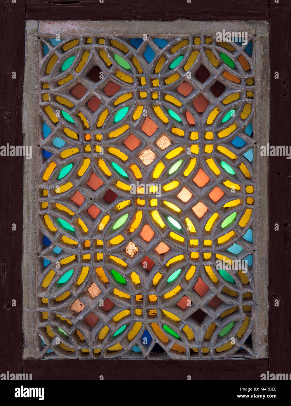 Perforated stucco window decorated with colorful stain glass with ...