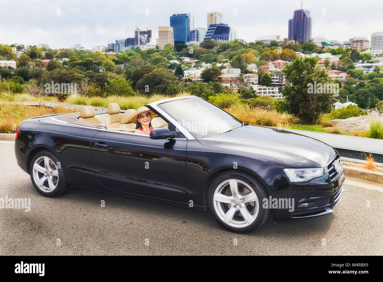 Side view of small convertible luxury roadster car with young lady ...