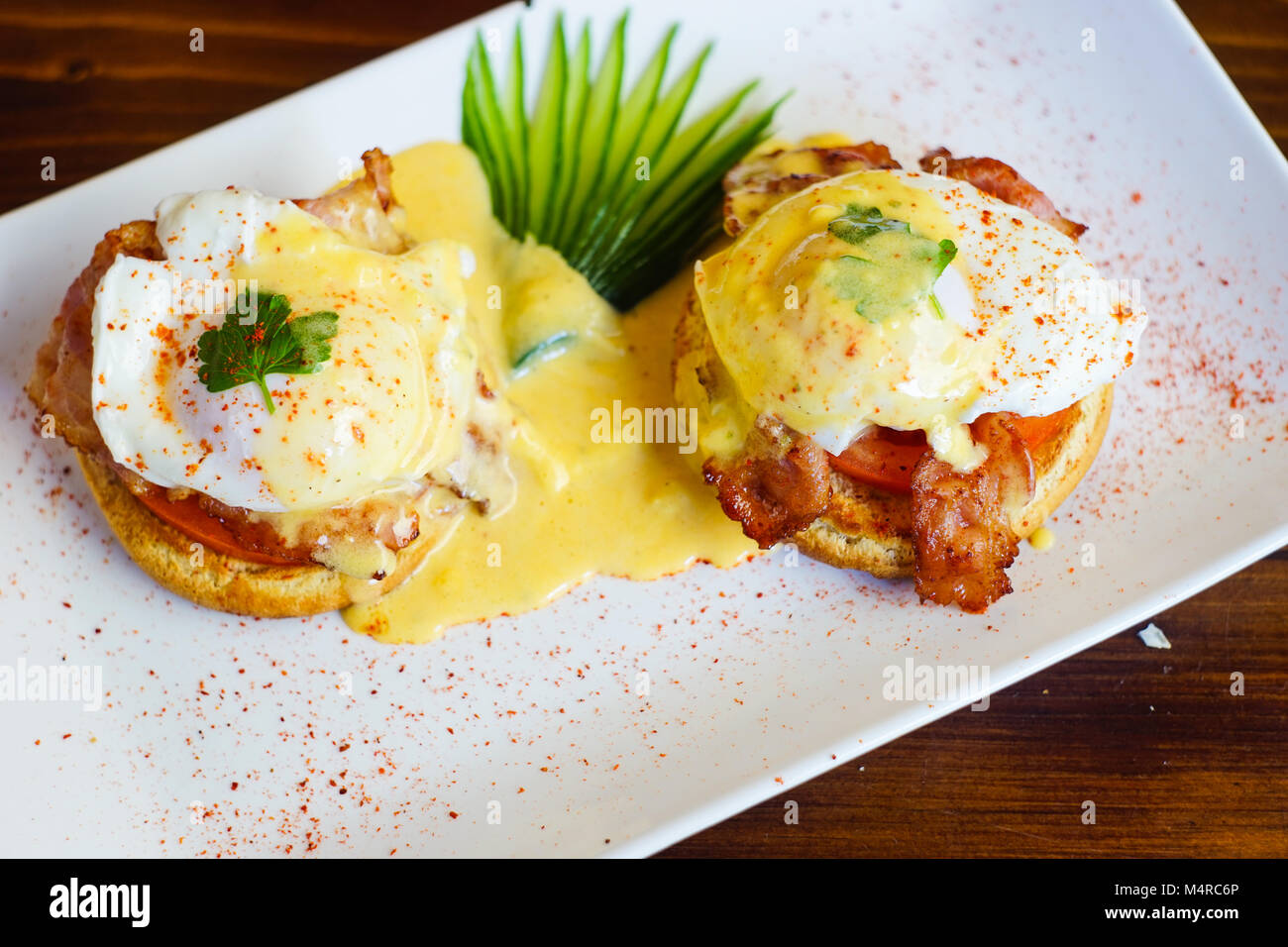 Rustic lunch set with benedict eggs and cucumber salad on dark wooden ...