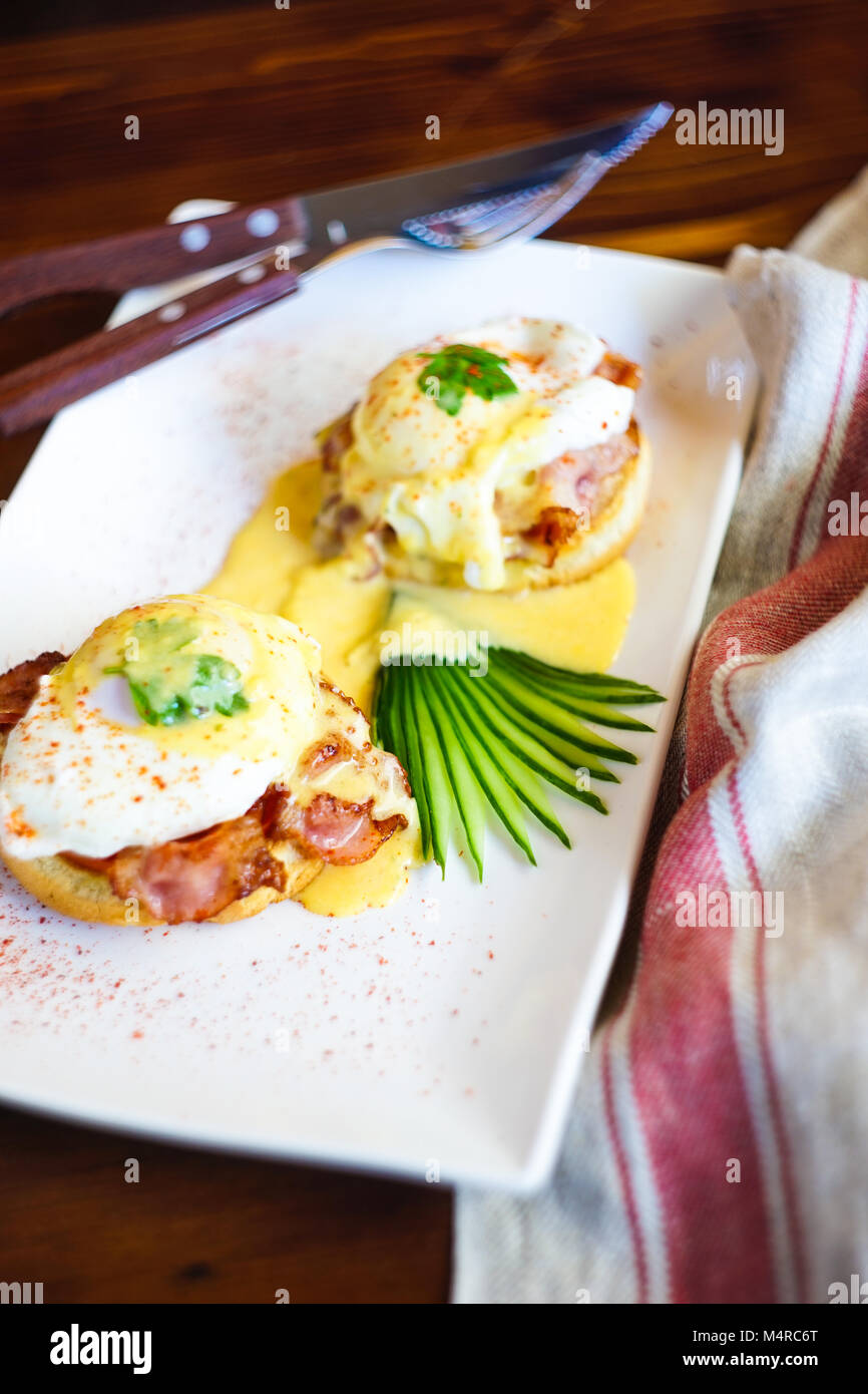Rustic lunch set with benedict eggs and cucumber salad on dark wooden ...