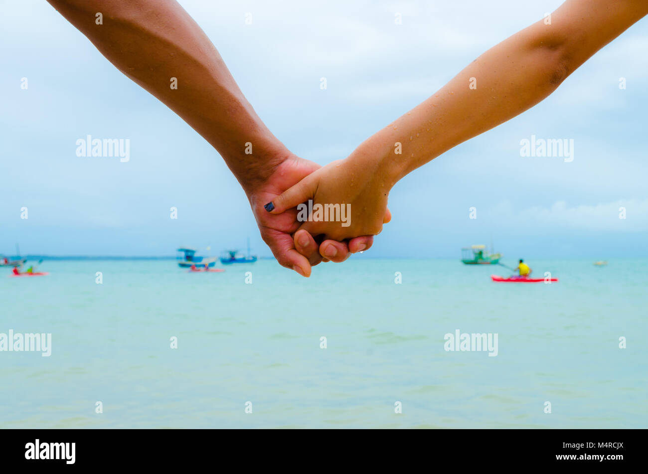 Couple holding hands having the sea as a background. View of the arms ...