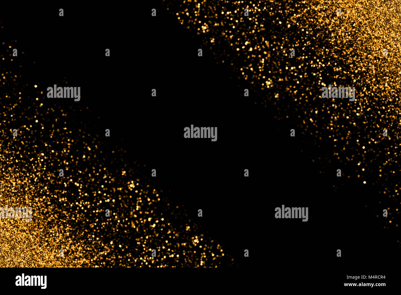 Defocused gold glitter with glowing sparks lights on a black background ...