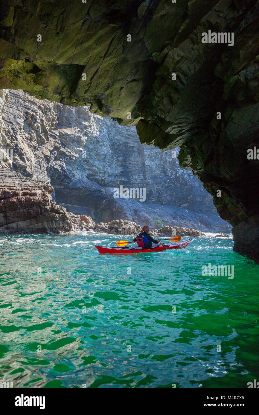 Sea kayaker exploring a cave near Glencolmcille, County Donegal ...