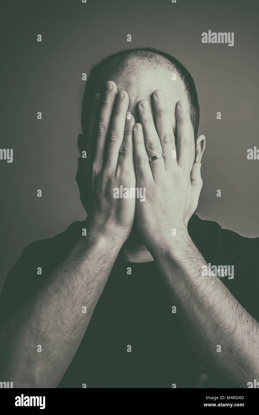 Monotone portrait of a man with a wedding ring covering his face with ...