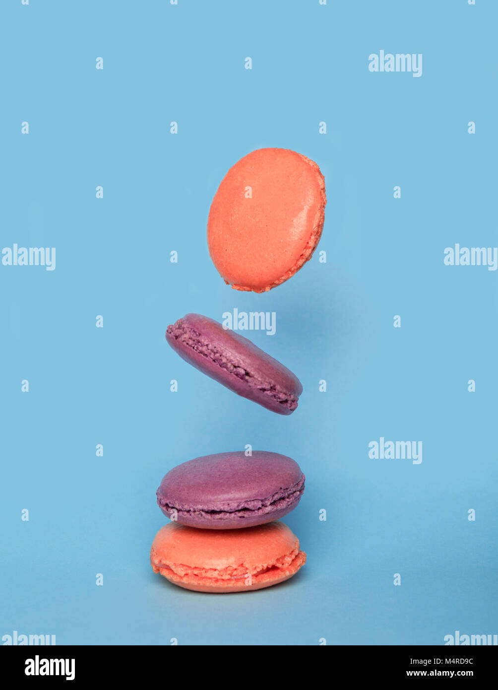 French macarons in motion falling on the blue pastel colored background ...