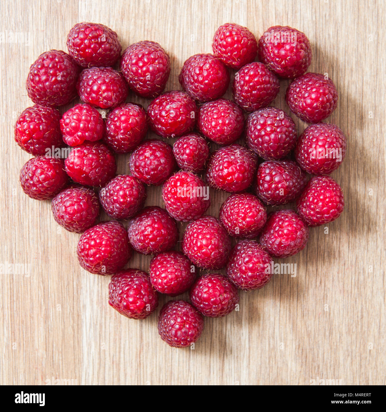 Raspberry berries heart symbol on wooden texture. Valentines day ...
