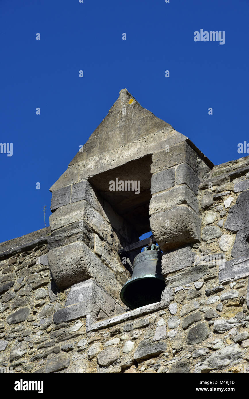 an old or antique historic bell tower built into a large old stone wall ...