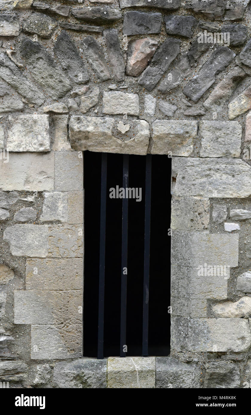 a barred gate in an old medieval stone wall. Gate or door to a dungeon ...