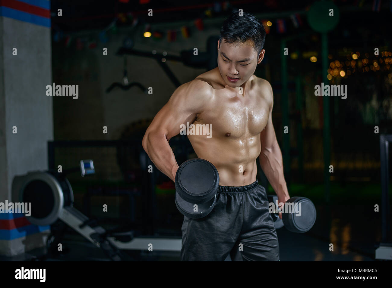 Young Chinese athletic man training in the gym. Make exercise with the ...