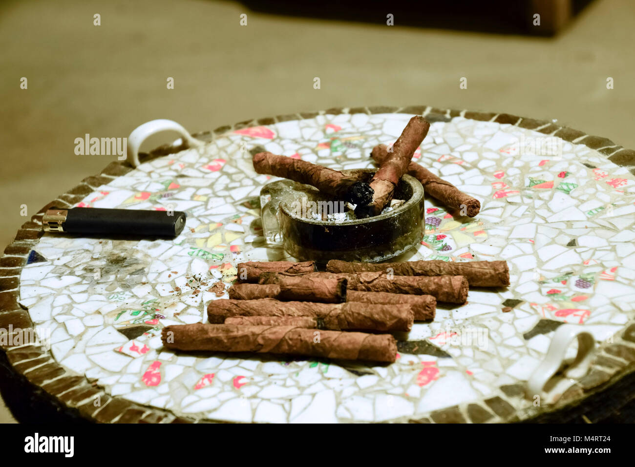 Homemade cigars from leafy tobacco leaves on a ceramic table. Ashtray ...