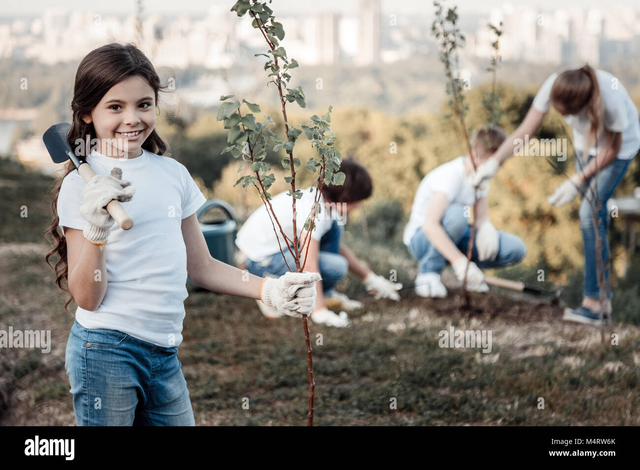 Delighted positive girl holing a young tree Stock Photo - Alamy