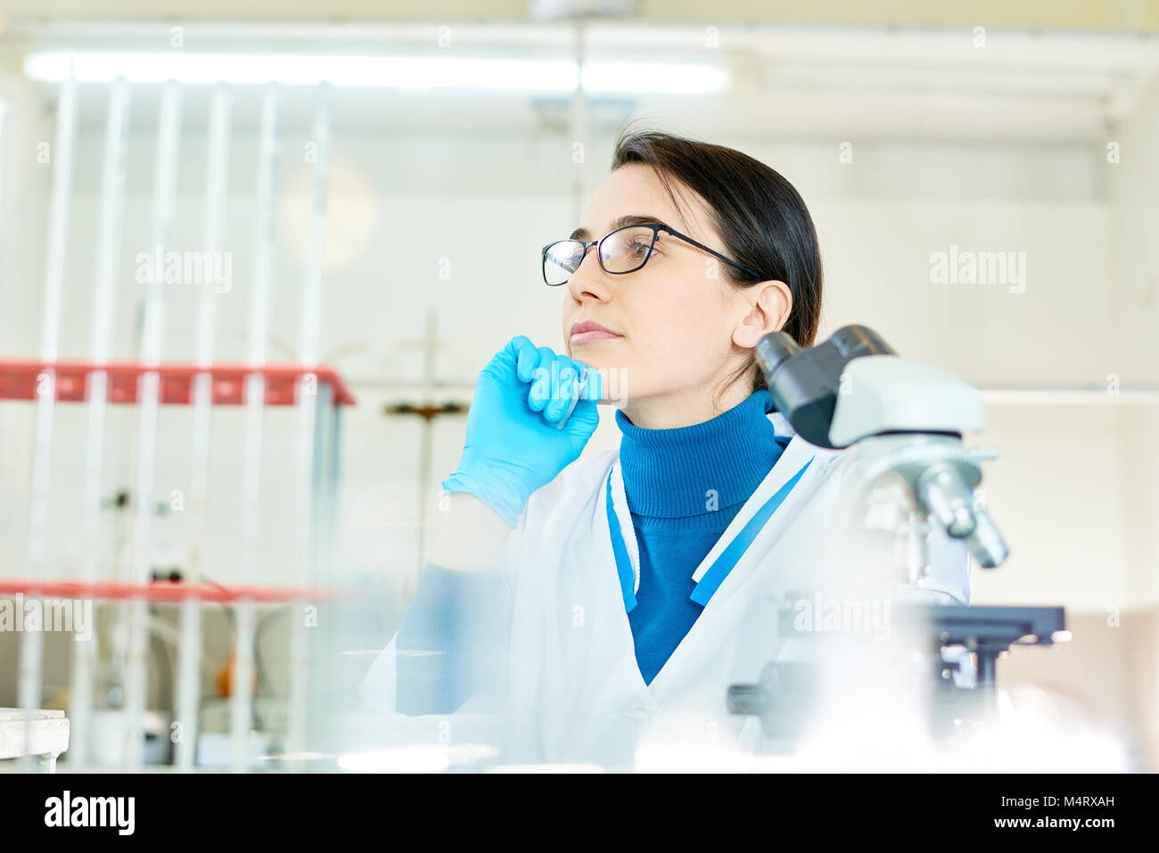 Waist-up portrait of pensive young scientist wearing eyeglasses and ...