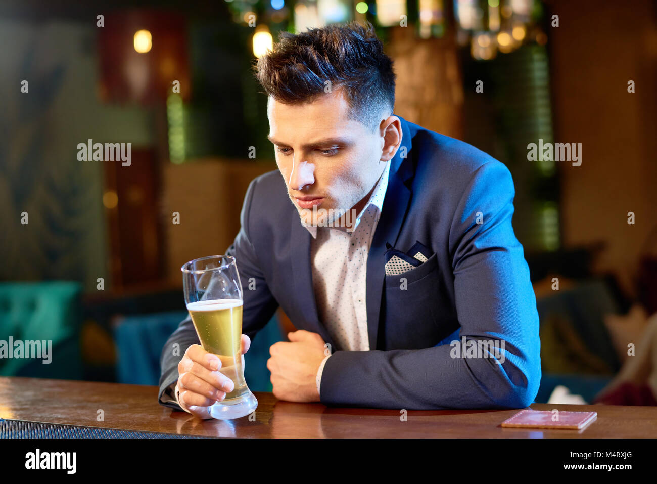 Waist-up portrait of handsome young businessman sitting at bar counter ...