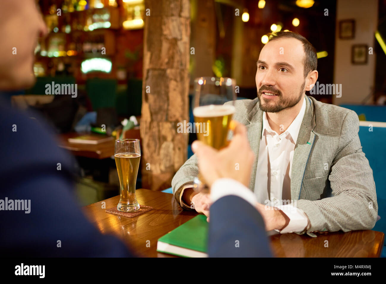 Two smiling business partners having informal meeting in pub: they ...