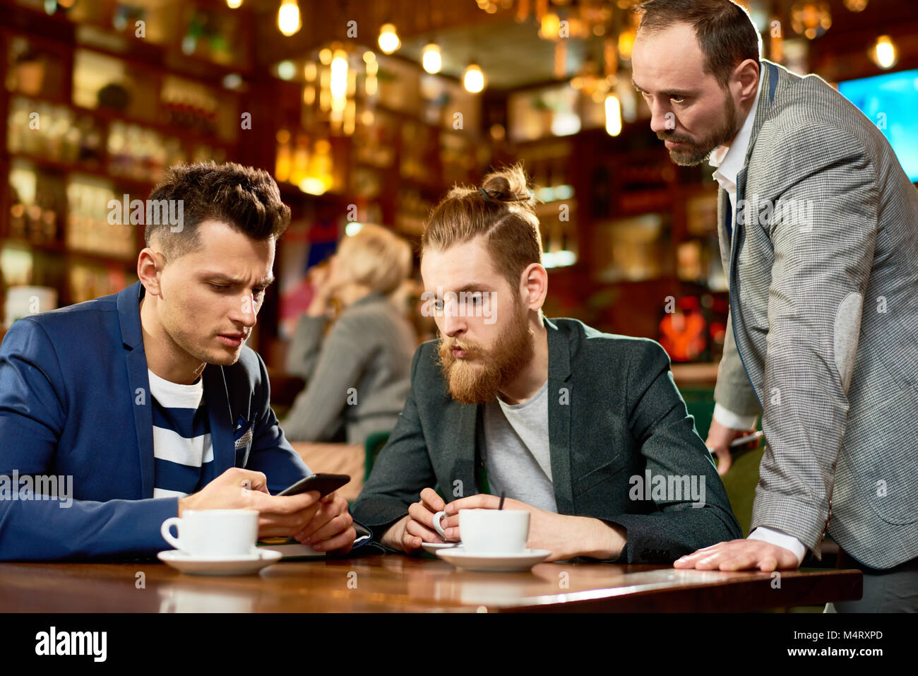 Handsome young manager using smartphone while having informal working ...